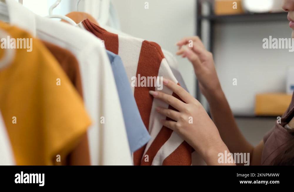 Close up female hands choosing many clothes on the rail hanging. Woman ...