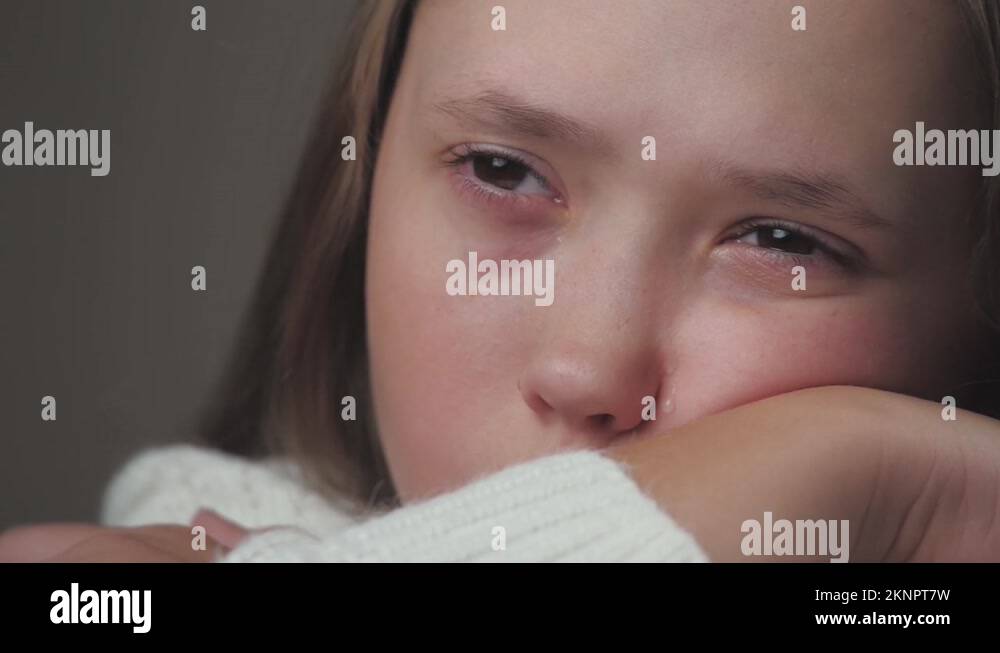 A teenage child cries and tears run down her cheeks. The girl is upset ...