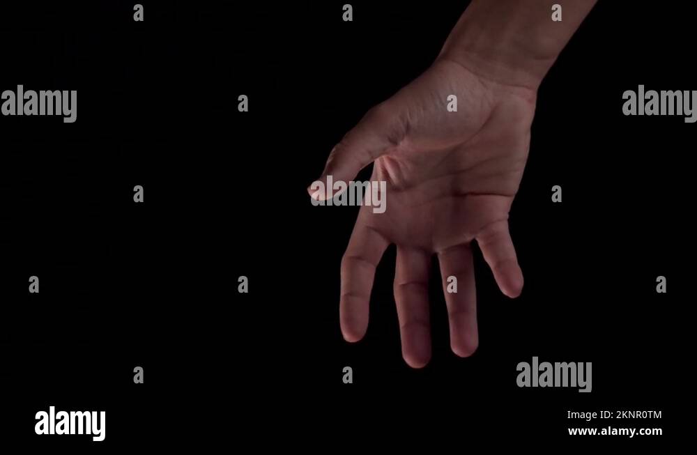 A human hand opening and closing, making a fist with a dark background ...