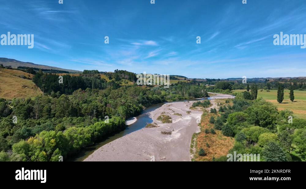 Aerial descent to the Pohangina riverbed, small trees, and grasslands ...