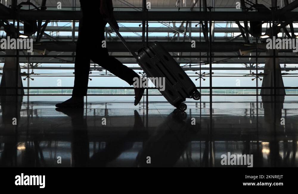 Traveler walks to boarding gate at terminal, low camera shows legs and ...