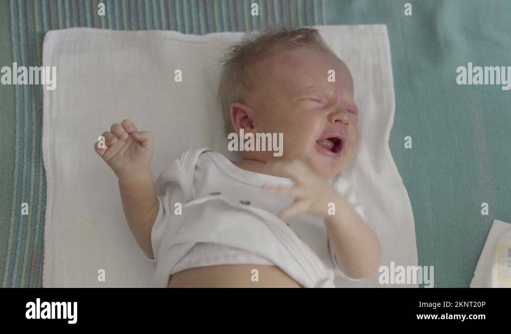 Toddler girl crying on a bed. Changing diapers of a newborn baby Stock ...