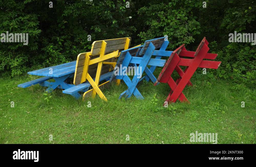 Old and colourful picnic benches stacked up on lawn. Yellow, blue and red Stock Video Footage ...