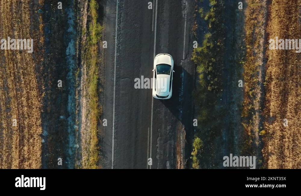 Road trip concept. Top view drone tracks modern white car moving fast ...