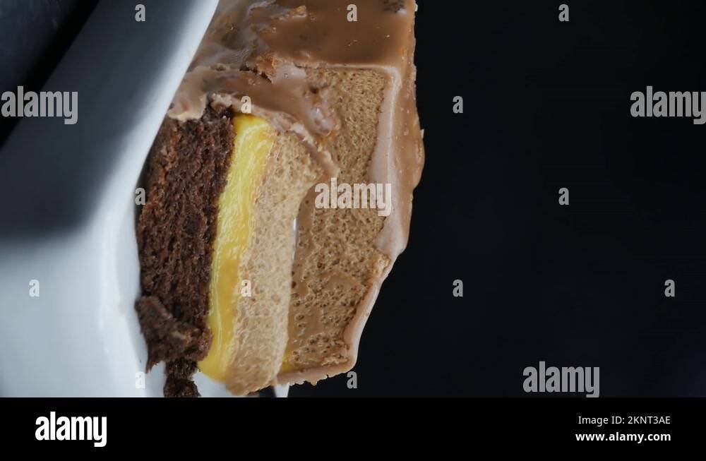 mousse cake with yellow filling and biscuit on a ceramic substrate ...