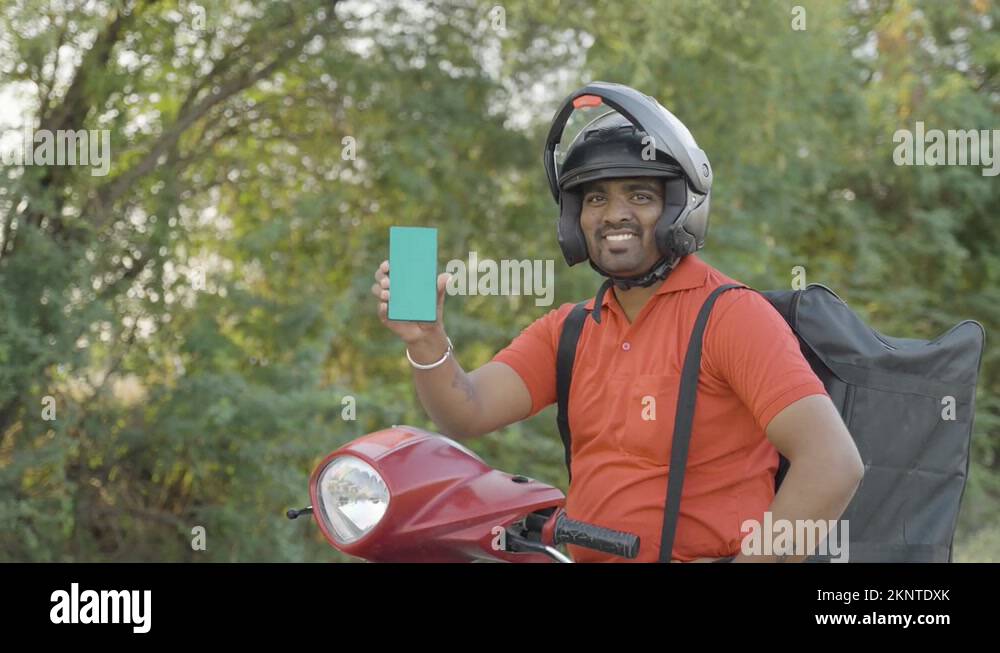 Indian happy delivery boy showing mobile phone with green screen mockup ...