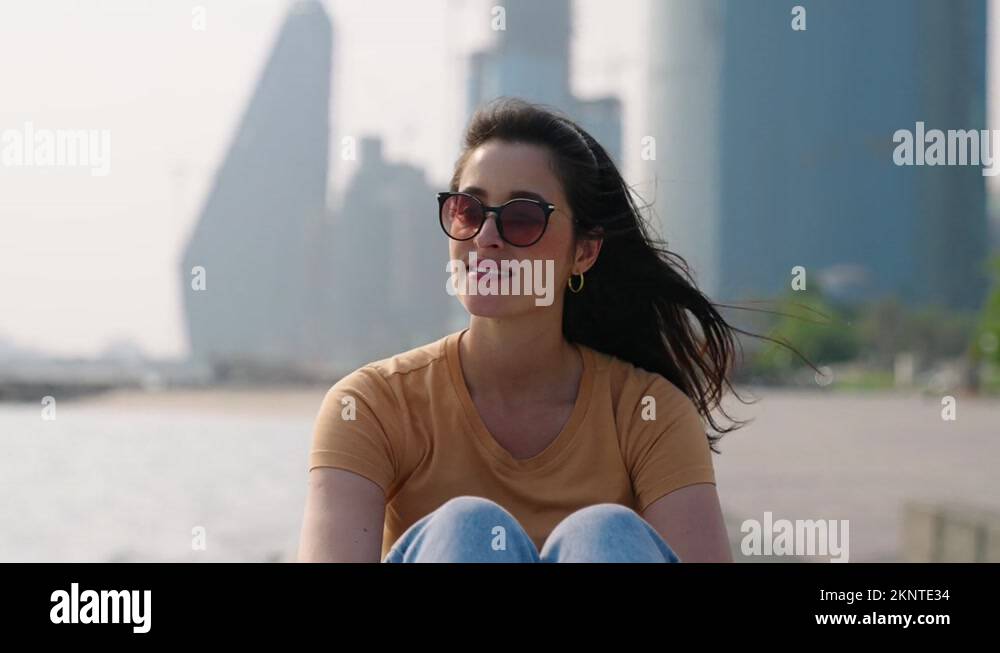 Woman tourist seated at corniche with skyline of Doha seen from Al ...