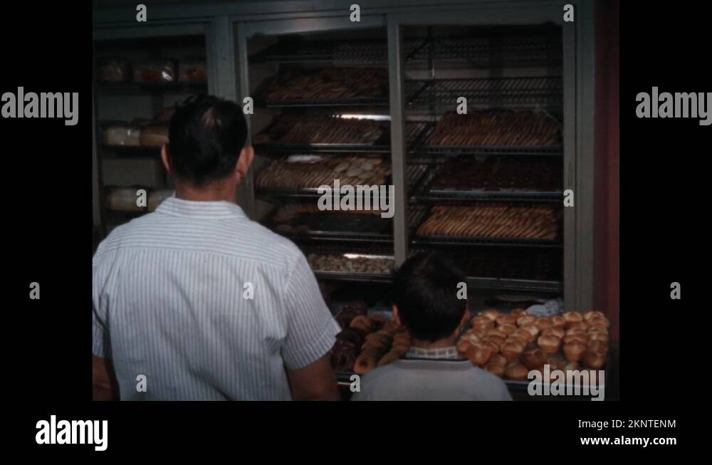 1960s: Man and boy at bakery counter, woman enters, man and boy exit ...