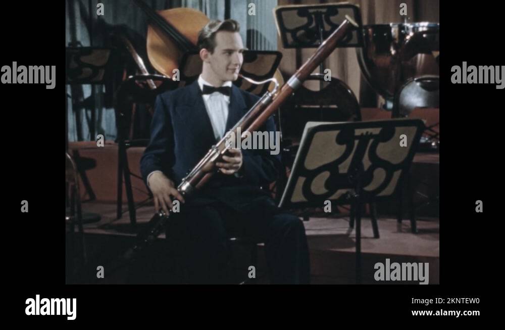 1950s: Man holding clapperboard, clapping. Man playing bassoon on stage ...