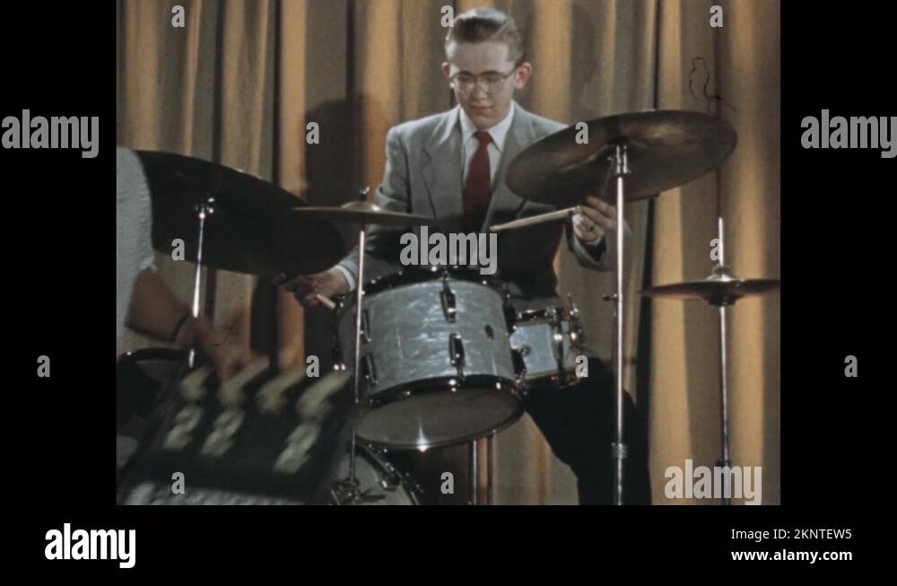 1950s: Man holding clapperboard, clapping. Man sitting at drum set ...