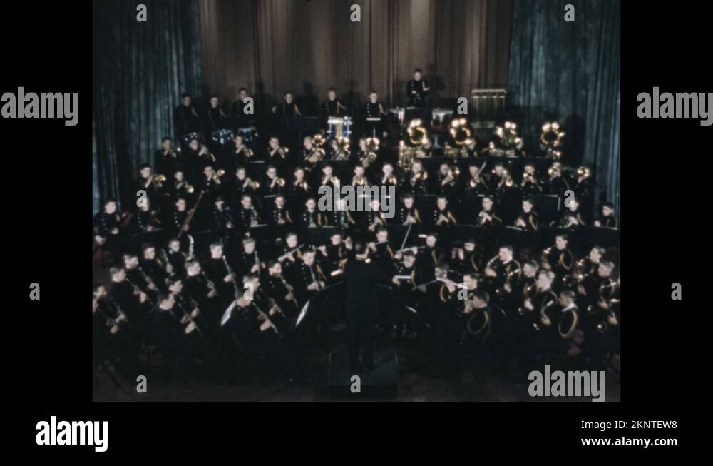 1950s: Man holding clapperboard, clapping, running. Symphonic orchestra ...