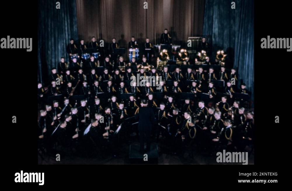1950s: Man holding clapperboard, clapping. Orchestra sitting on stage ...