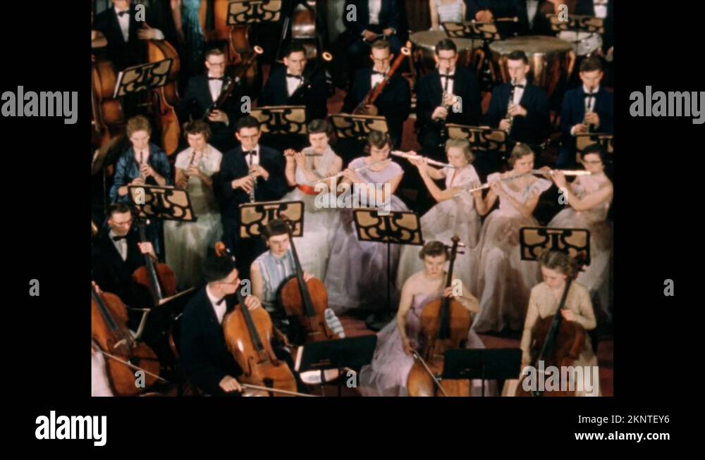 1950s: Man holding clapperboard, clapping. Orchestra performing on ...