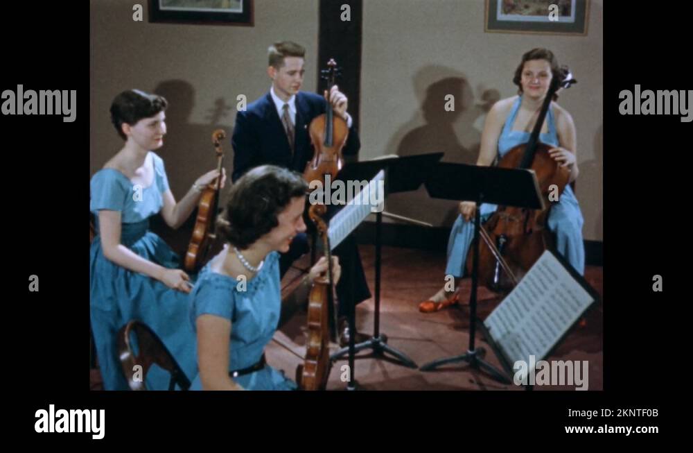 1950s: Man holding clapperboard, clapping. Musicians playing string ...