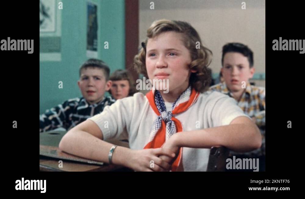 1950s: Girl shakes head and speaks at desk in classroom. Children ...