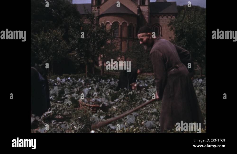 1960s: Exterior medieval church with monks working in garden, hoeing ...