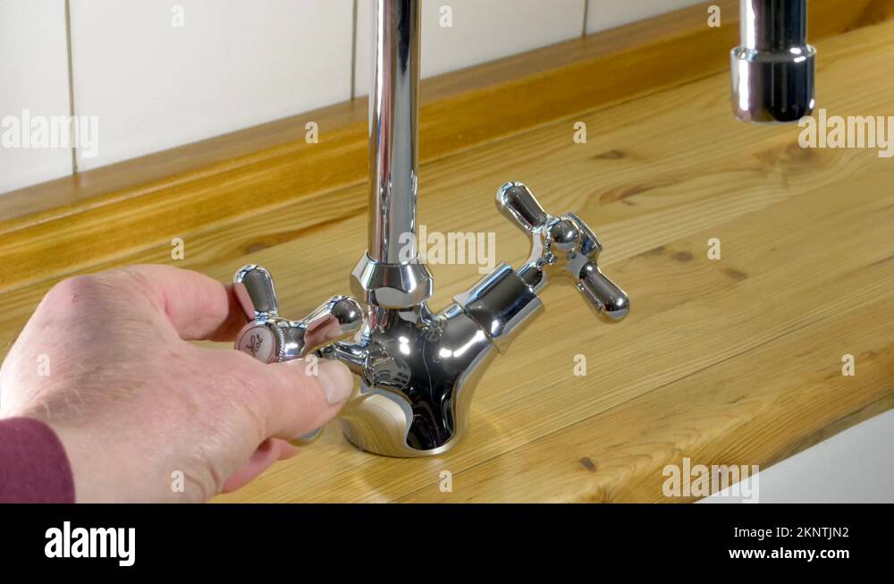 Man's hand turning on a traditional hot tap in a pine kitchen counter ...