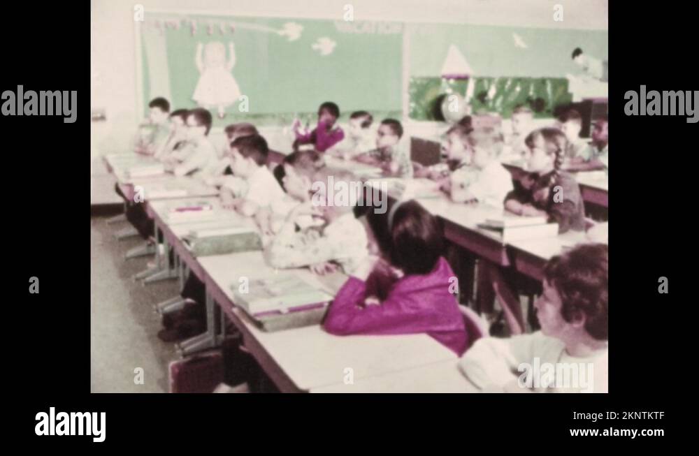 1960s: Children sitting at desks in classroom. Students reciting in ...