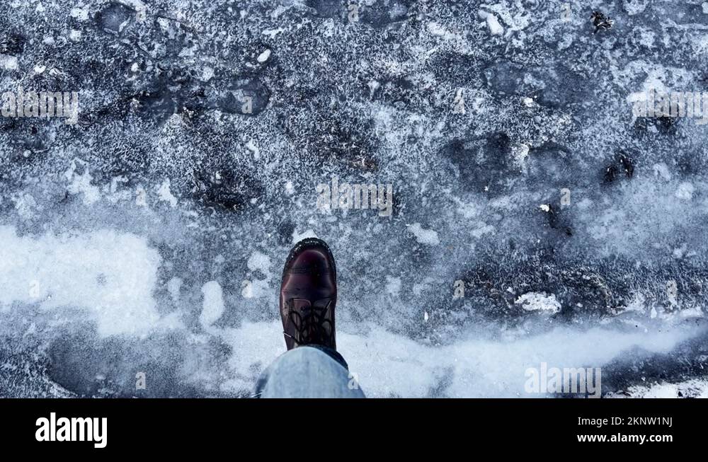 Man in boots steps on ice at frozen lake Stock Video Footage - Alamy