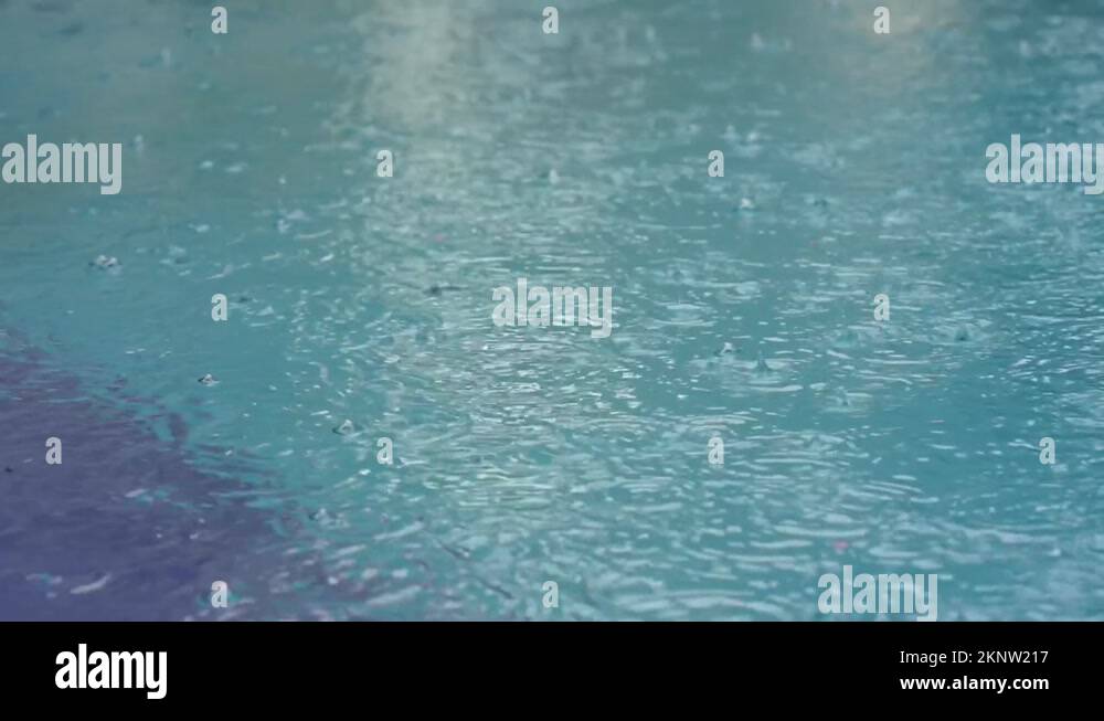 rain falling into the pool filmed in slow motionWater surface with ...