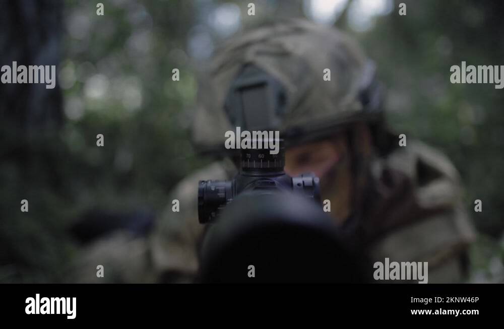 Armed special forces soldier with a sniper rifle in an ambush in dense ...