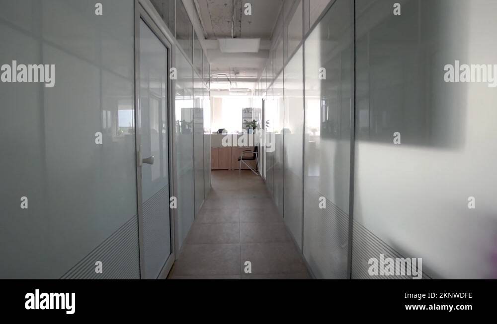 The camera pans the narrow aisle of the office complex past the doors ...
