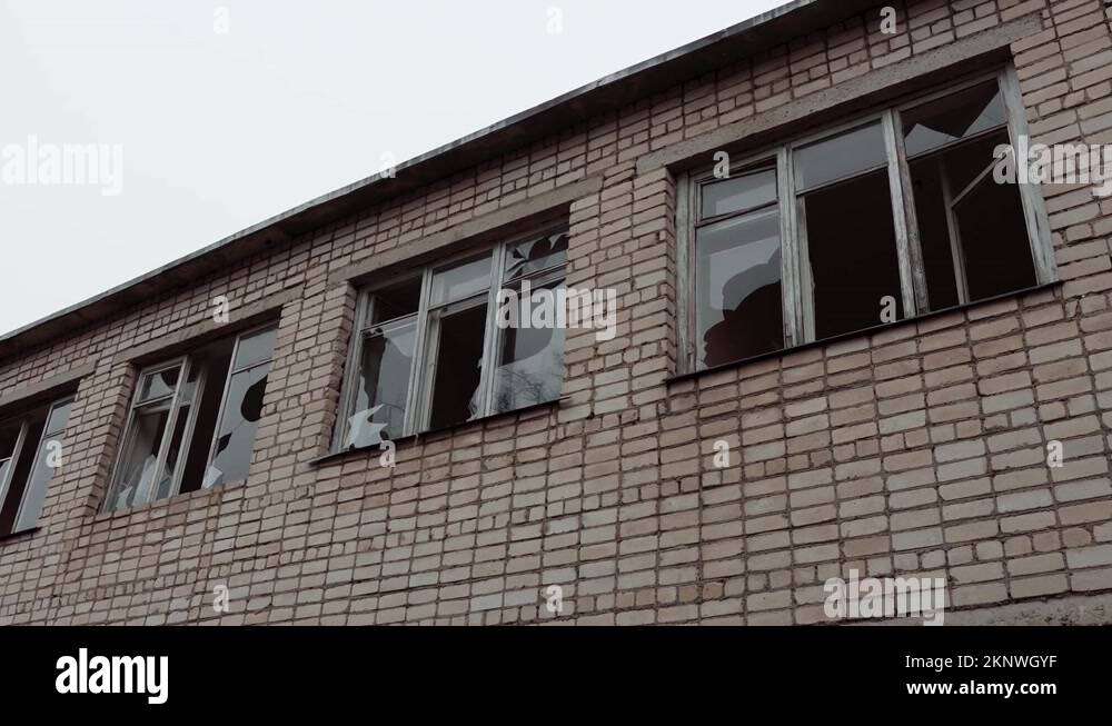 Broken windows in a brick two-story building. An abandoned vandalized ...