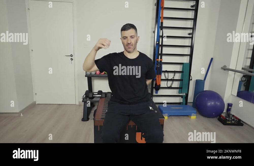 A man stretches his neck muscles before a workout at his small home gym ...