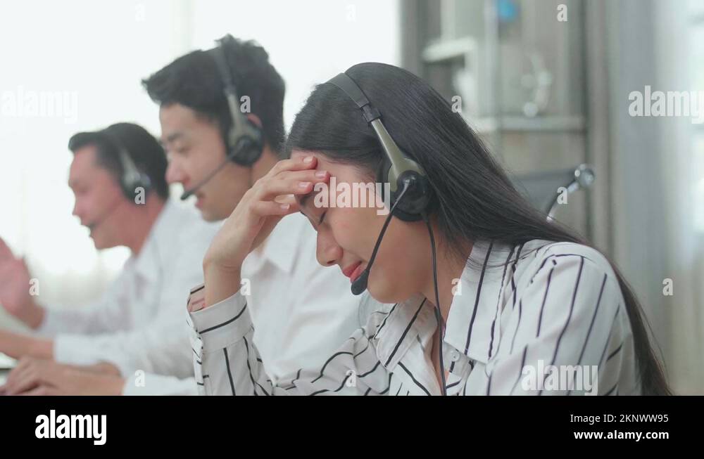 A Woman Of Three Asian Call Center Agents Wearing Headset Is Tired Due ...