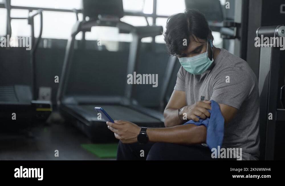 young indian body builder with medical face mask cleaning sweat while ...