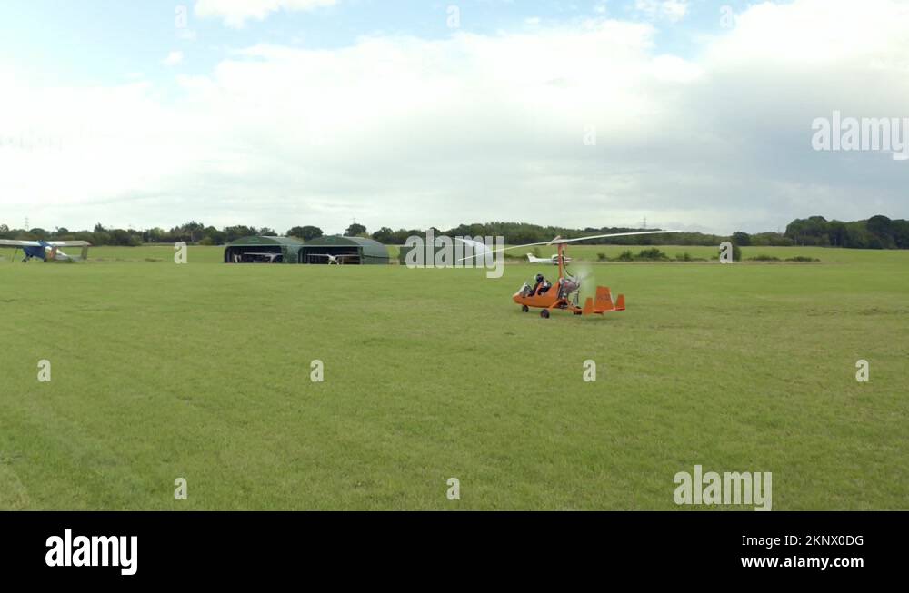 Gyrocopter 4K. slowly following behind craft along grass towards launch ...