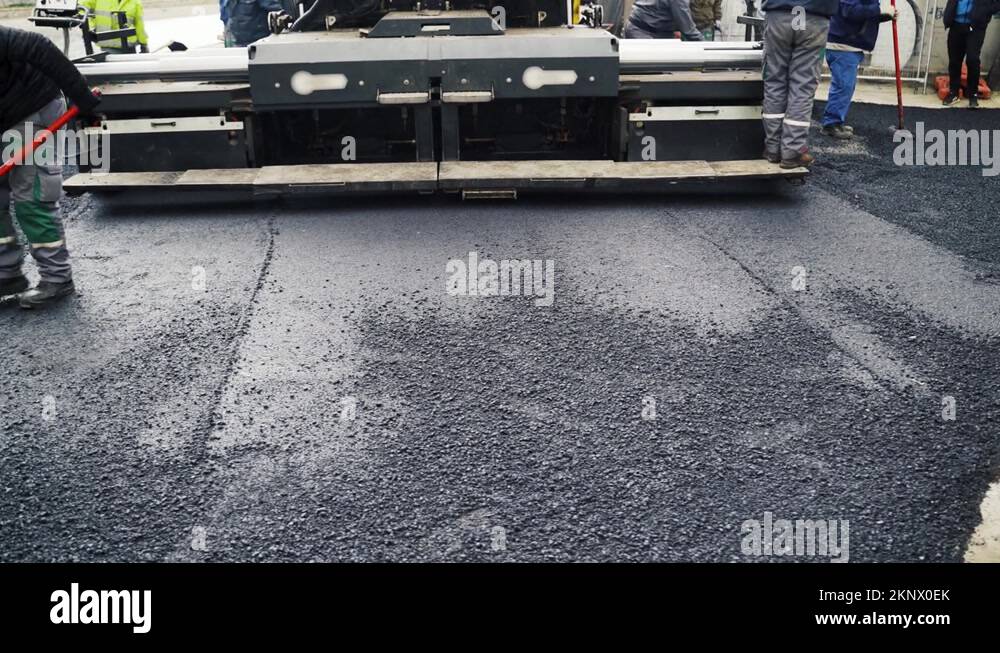 Paving laborers leveling fresh asphalt on a road construction site ...
