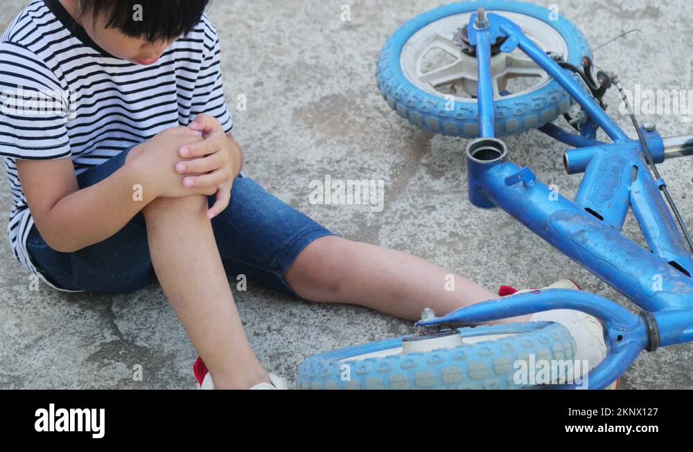 Sad little girl sitting on the ground after falling off her bike at ...