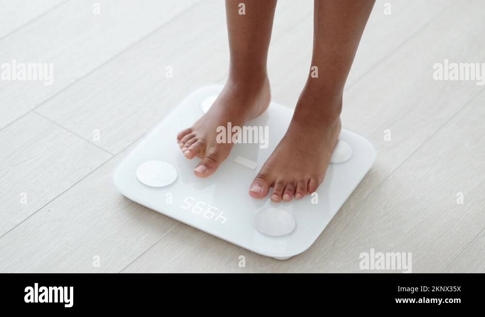 Legs of black girl standing on scale to measure weight. African ...