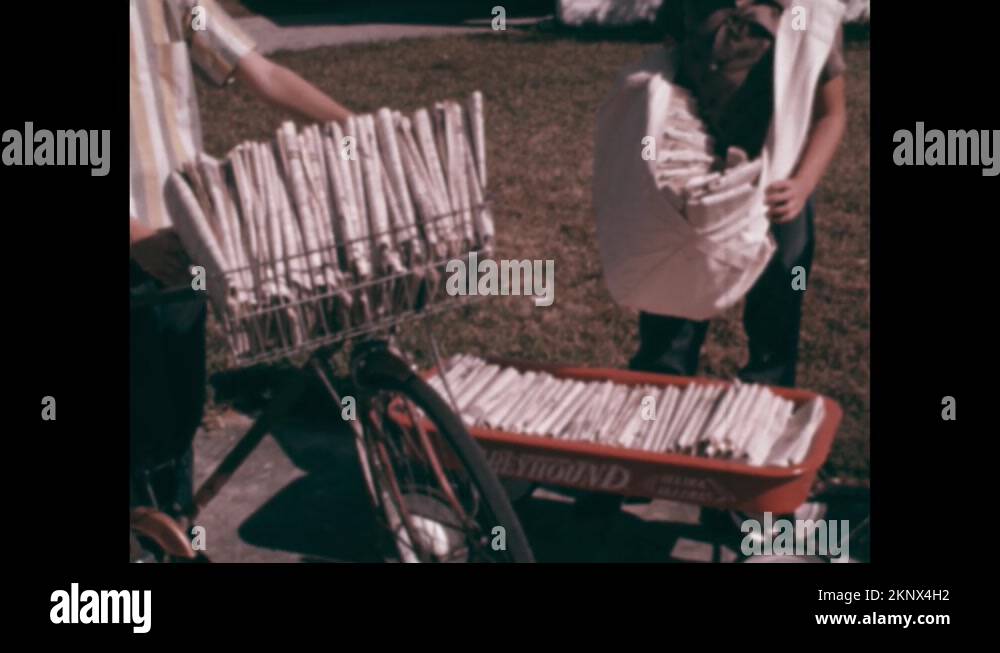 1960s: Two newspaper delivery people with newspapers in wagon and on ...