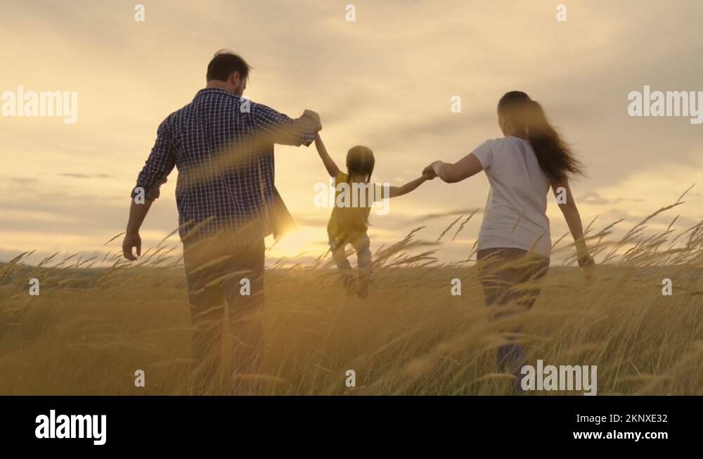 Happy family runs in park, sunset. Dad, mom, kid, daughter run, jump in ...