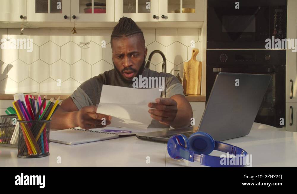 Shocked handsome African American man receiving eviction notice at home ...