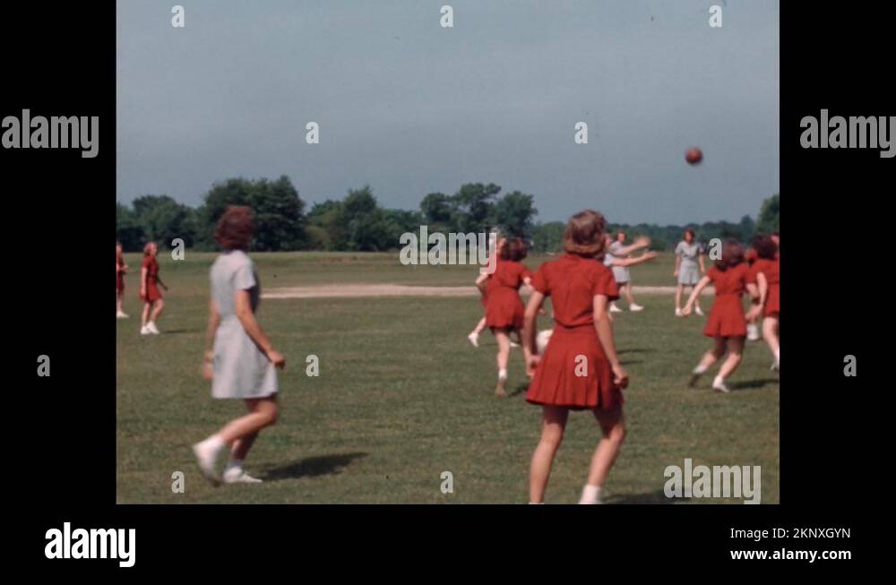 1940s: Girls play speedball on outdoor field. Teams toss and kick ball ...