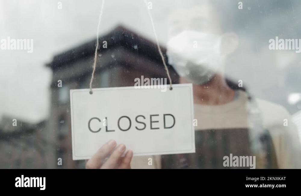 Waiter turn open close sign entrance door while reopening cafe during ...