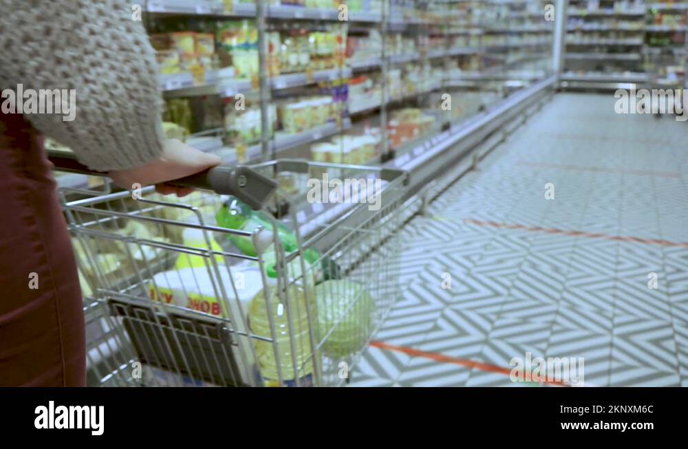 Close-up of a young woman's hands moving a grocery cart through the ...