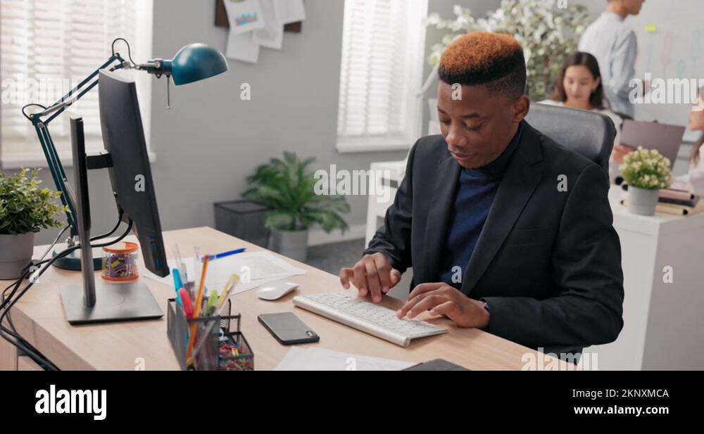 Elegant man working in an office boy is sitting behind desk in front of ...