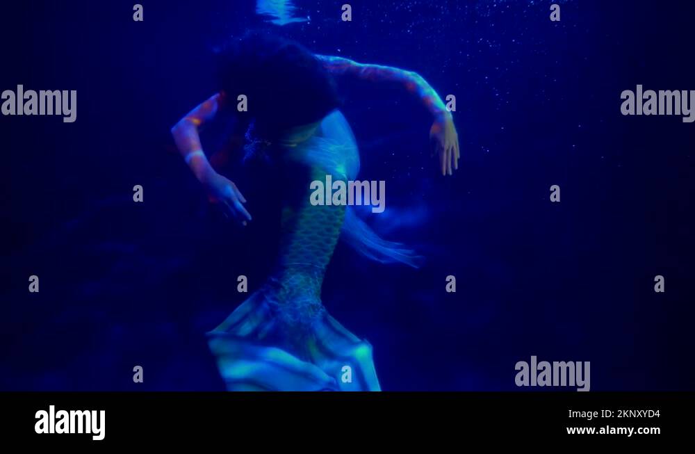 enigmatic mermaid with big tail is floating in blue depth of ocean ...