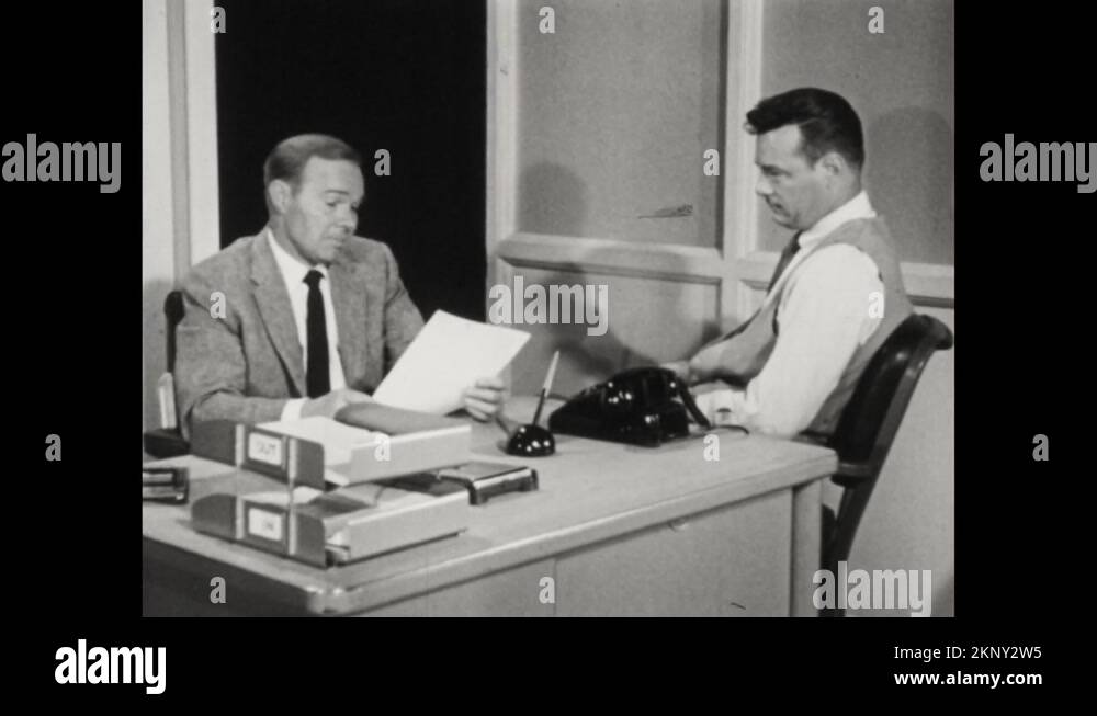 1960s: In office set-up, one man behind desk and the other next to him ...