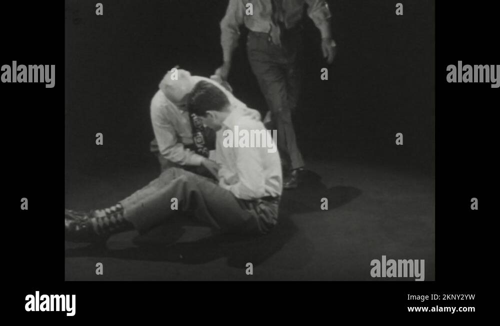 1940s: two men coming to help man sitting on floor with hurt arm Stock ...