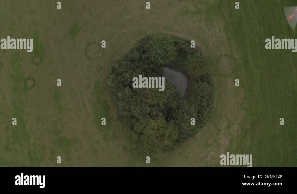 Gyrocopter topdown drone rising shot above circular tree as gyro enters ...
