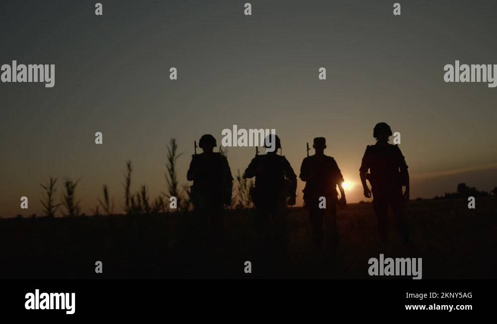 Two armed men with weapon walking across field after combat operation ...