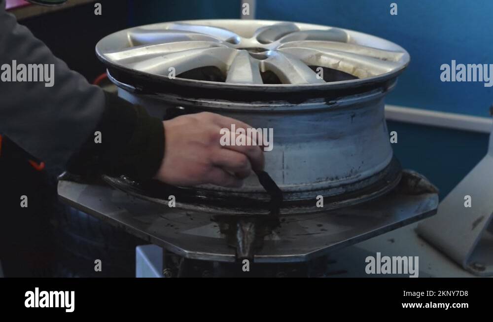 An auto mechanic smears a car disc with a sealant when installing a ...