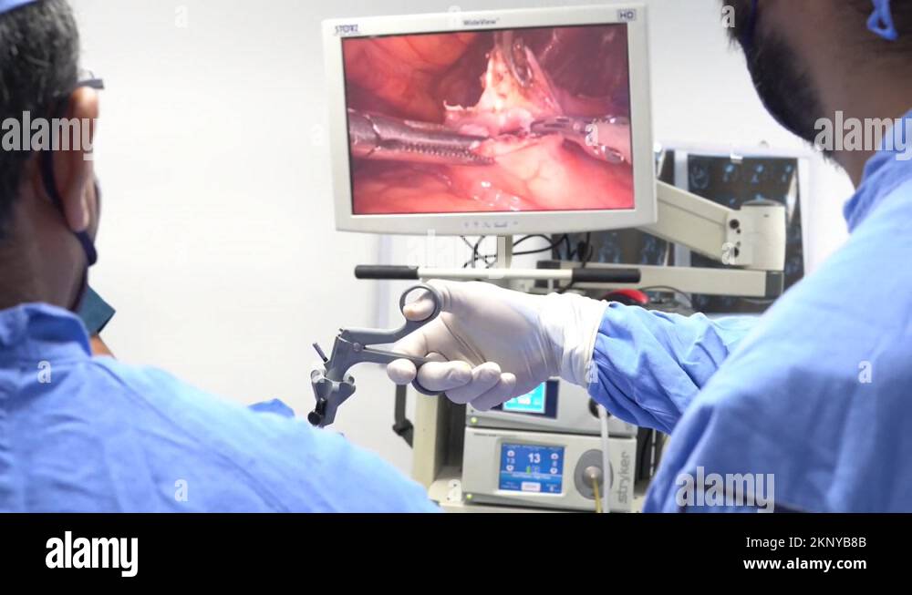 Back view of surgeons team looks at monitors while preforming operation ...