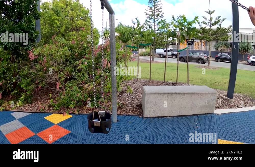 Side view of a young boy swinging high at a colourful new playground. The Stock Video Footage ...