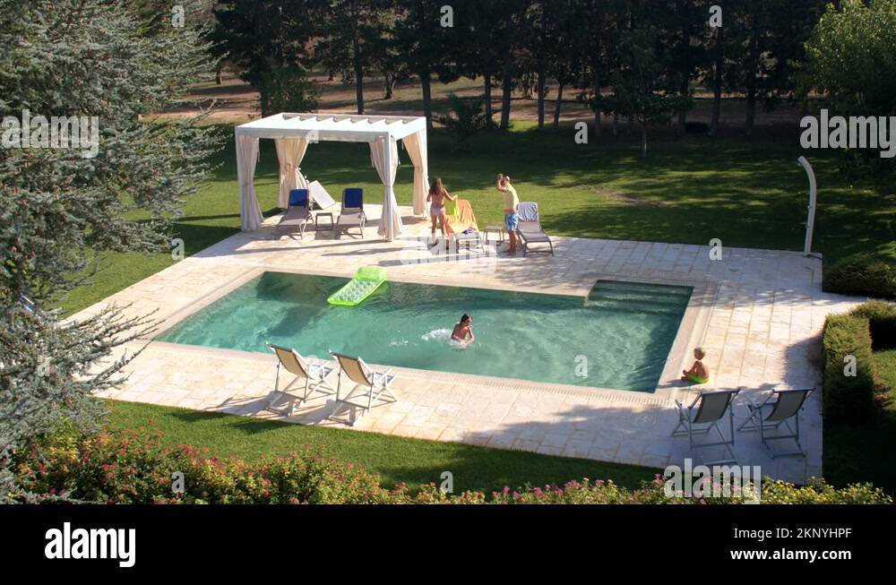 Child jumps into outdoor pool, swims with supervision of sunbathing ...